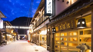 Uma rua tradicional japonesa à noite, com edifícios iluminados e chão coberto de neve.
