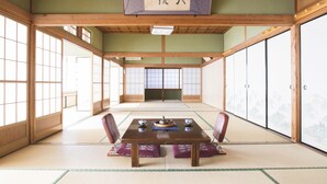 Um quarto japonês tradicional com tatames, uma mesa de madeira baixa e portas deslizantes.
