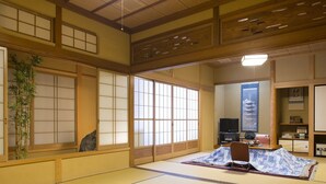 Um quarto japonês tradicional com tatames, portas deslizantes shoji e uma televisão.
