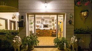 Entrada de hotel com balcão de recepção, quadros nas paredes e estátuas decorativas.