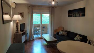 Sala de estar com televisão, sofá e mesa de jantar.