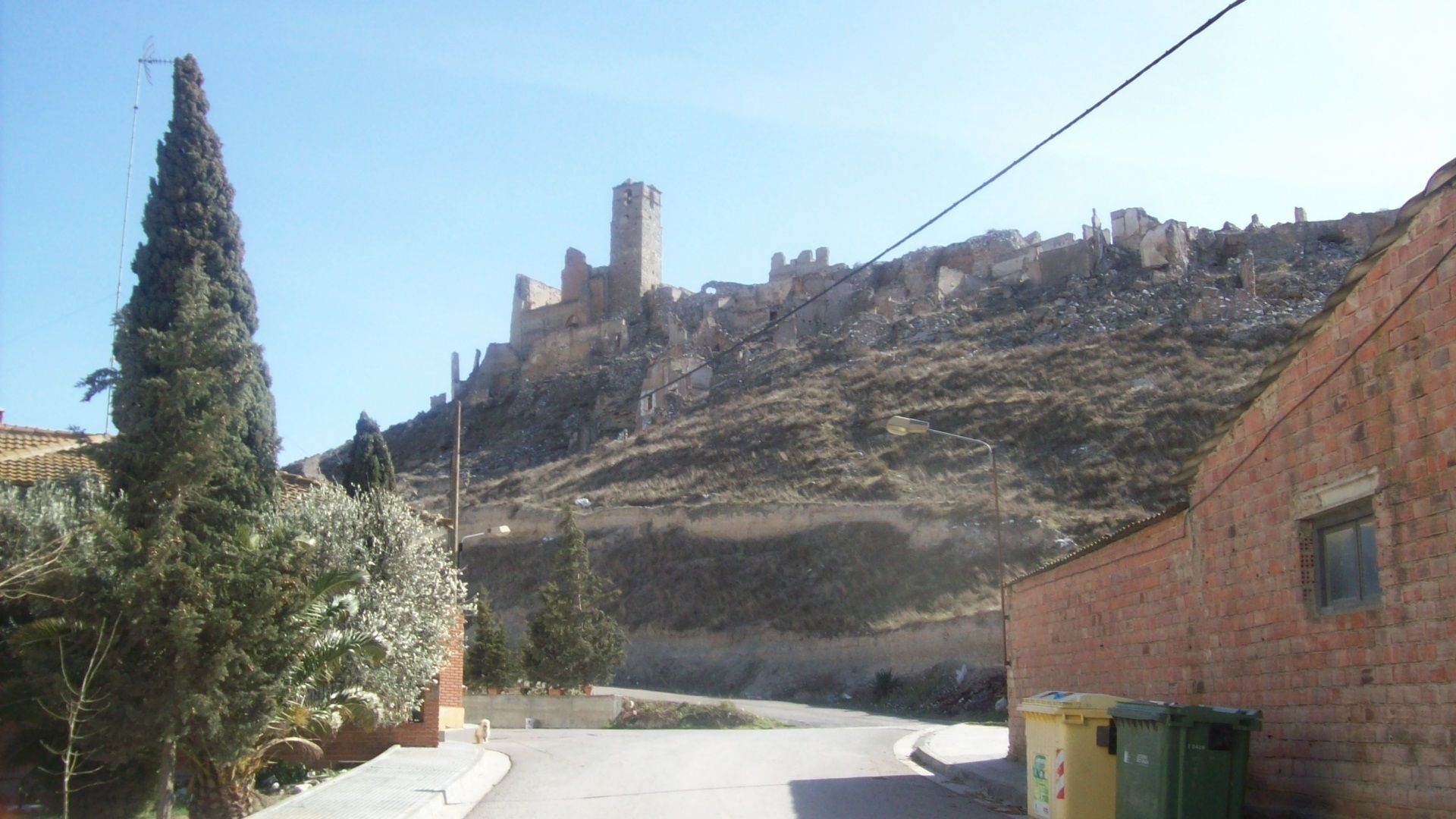 Uma rua que sobe até uma colina com ruínas de um castelo.