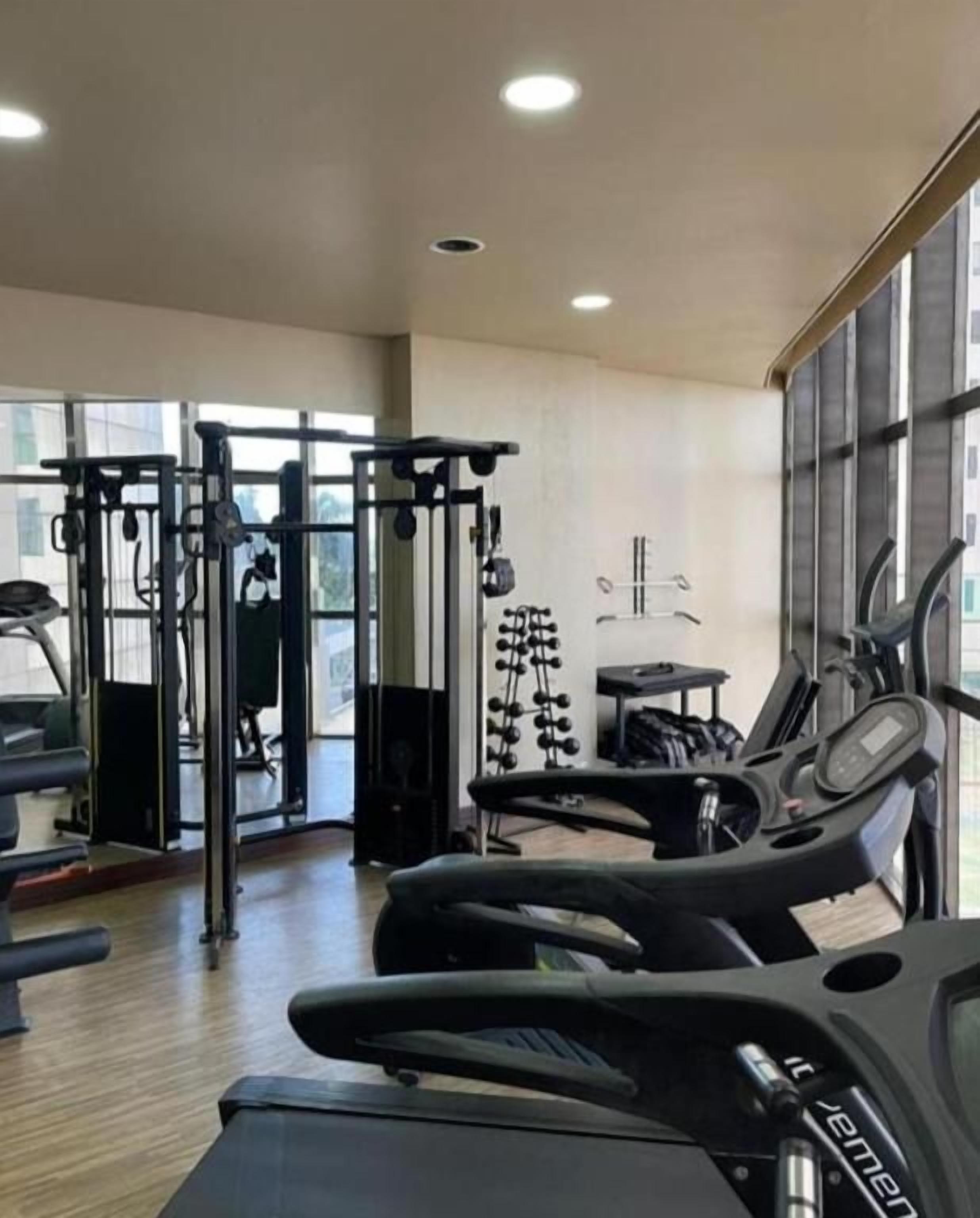 Academia com esteiras, aparelhos de musculação e espelhos.