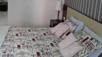 Quarto de hotel com uma cama, ar condicionado, uma luminária e parede listrada.