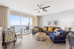 Uma sala de estar ampla com varanda, ventilador de teto e vista para o mar.