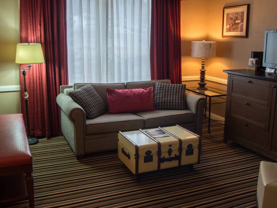 Quarto de hotel com sofá, uma mesinha, armário e mala.