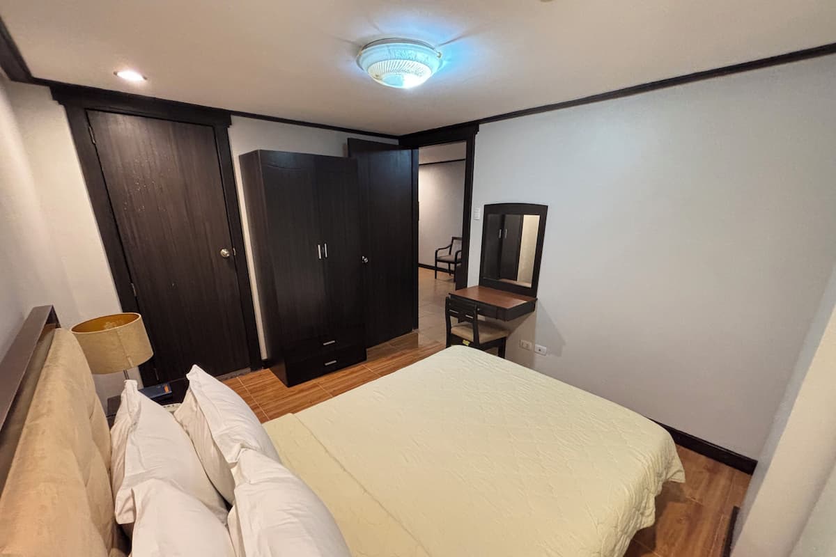Quarto com cama, escrivaninha, cadeira, guarda-roupa e espelho.