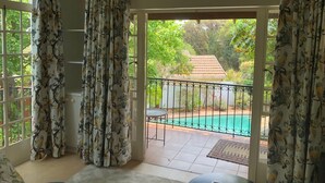 Quarto com vista para uma piscina, varanda e uma porta com cortinas.