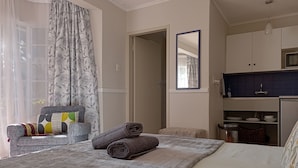 Quarto com cama, sofá, espelho e kitchenette.