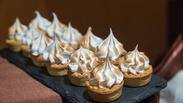 Uma fileira de mini tortas com chantilly em uma tábua de ardósia.