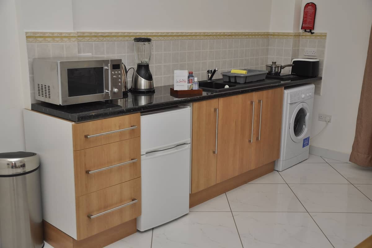 Cozinha equipada com micro-ondas, liquidificador, torradeira e máquina de lavar.