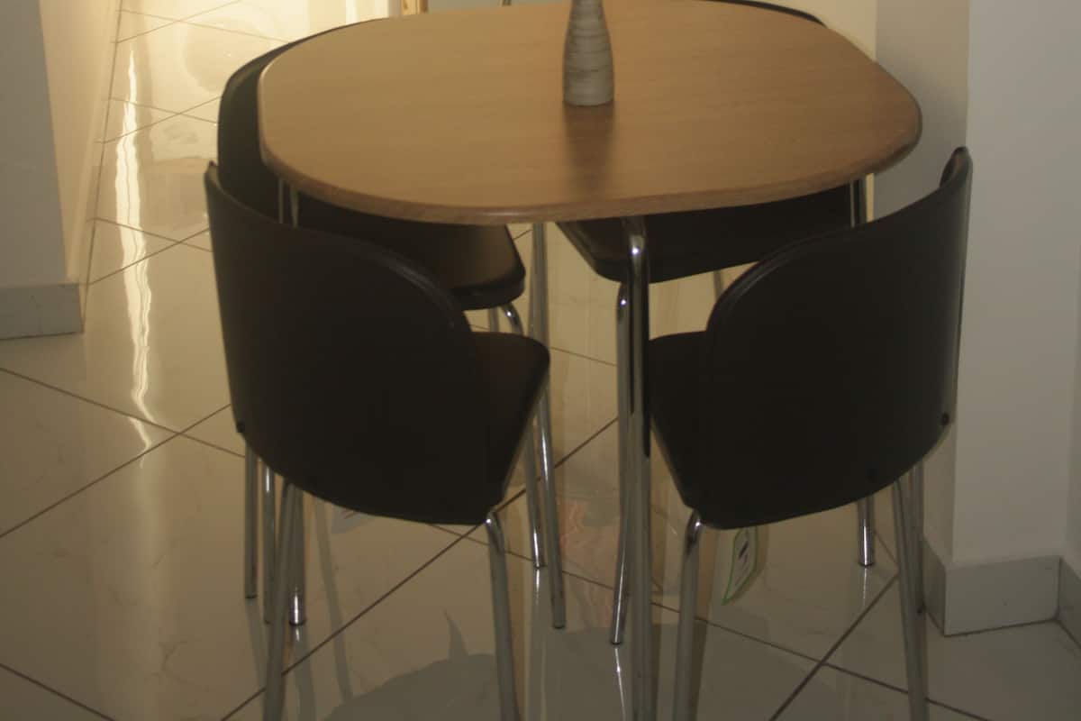 Cozinha compacta com máquina de lavar, micro-ondas e área de refeições com mesa e cadeiras.