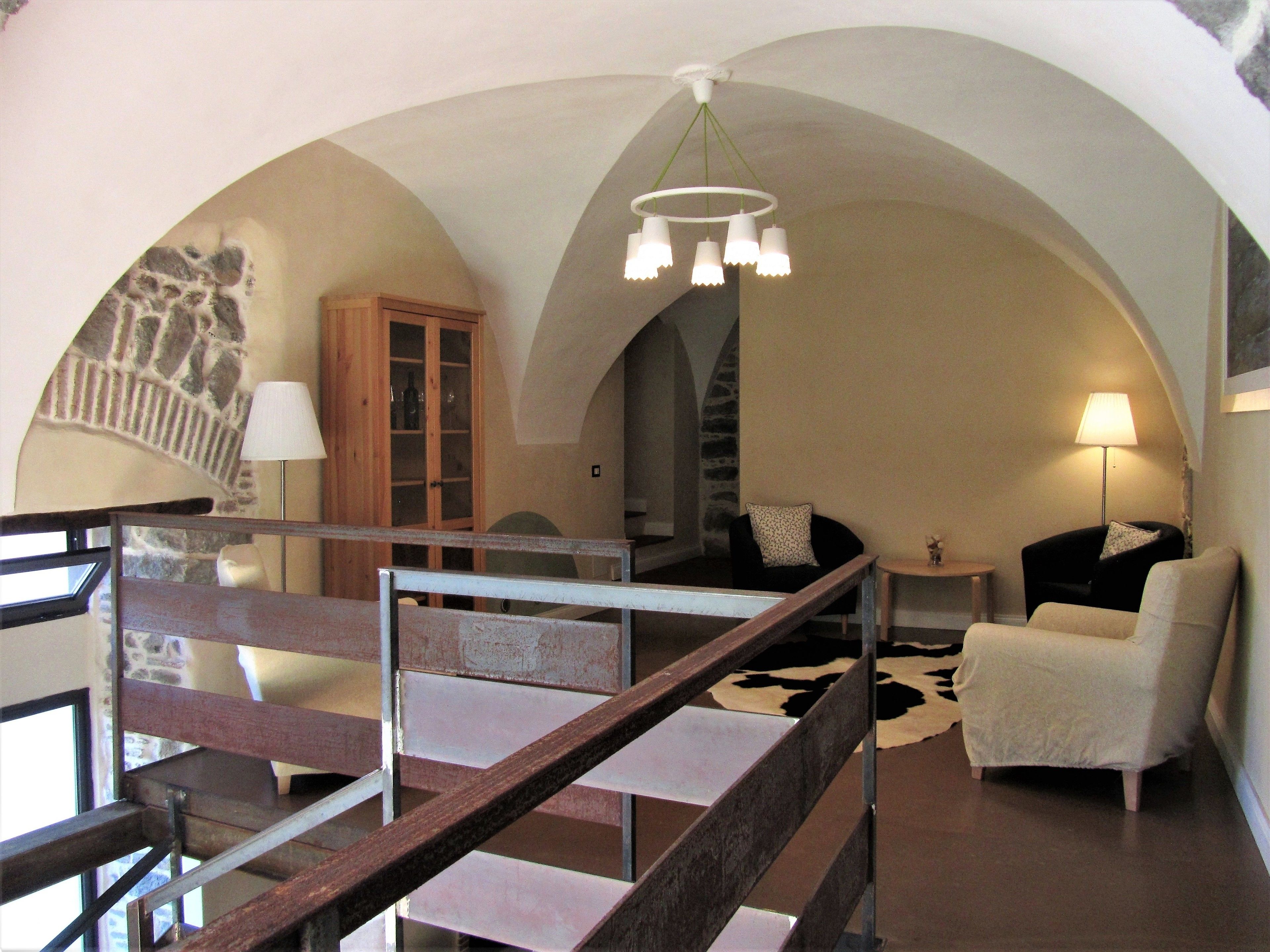 Uma sala ampla com escada, armário de madeira e tapete de couro.
