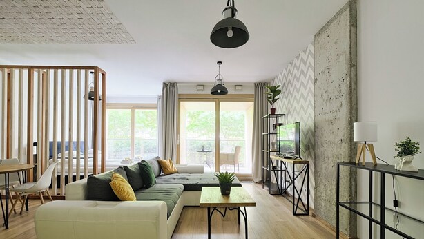 Uma sala de estar moderna com um sofá seccional, uma mesinha com uma planta, uma televisão e uma estante de livros.