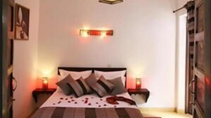 Quarto com cama grande, duas mesas de cabeceira, luminária pendente e tapete vermelho.