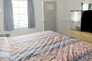 Quarto com cama, cômoda, televisão e janela com cortinas.