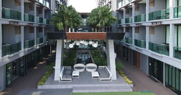 Um átrio de hotel moderno com área de estar central, várias varandas e uma piscina.