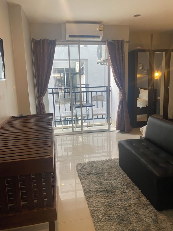 Sala de estar com sofá, mesa de madeira e varanda com cadeiras e mesa.