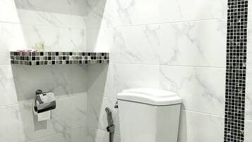 Casa de banho com sanita, chuveiro e parede revestida a azulejos.