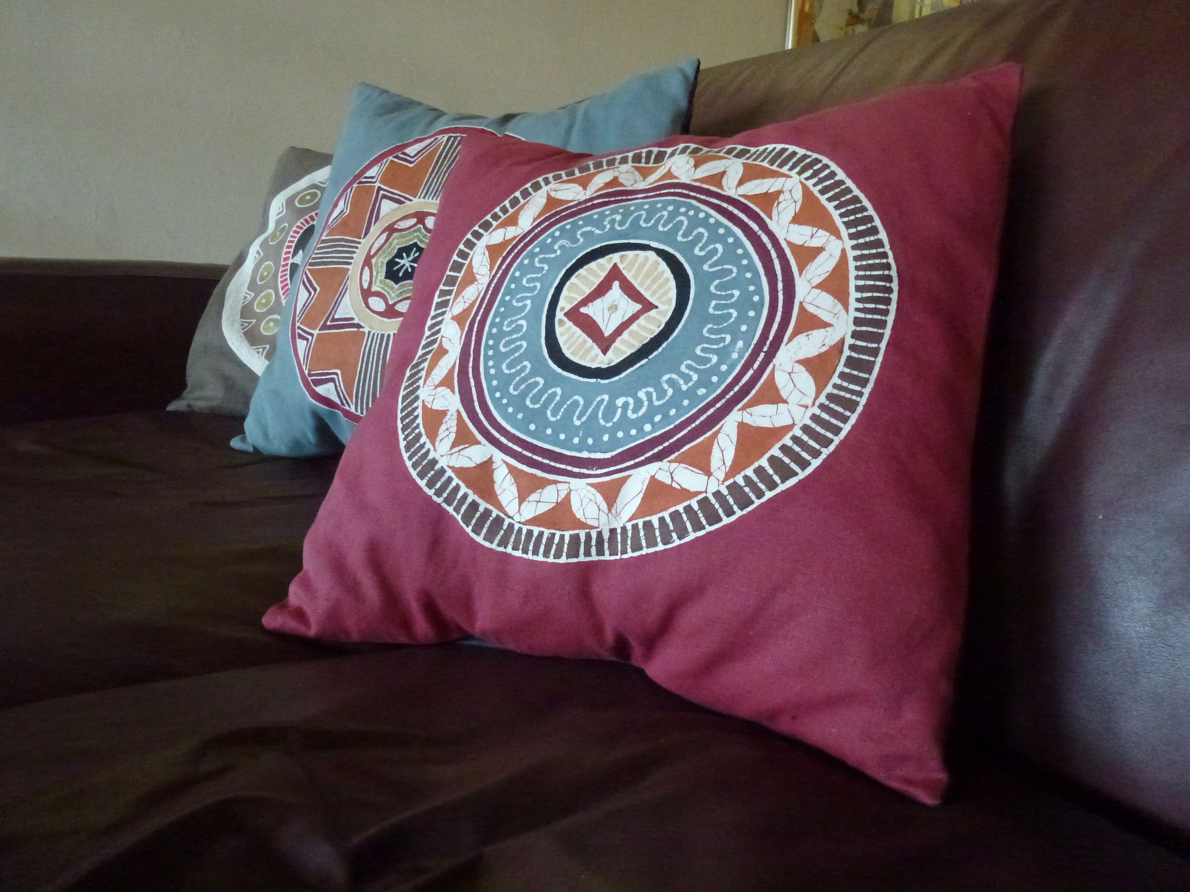 Um sofá de couro marrom com almofadas decorativas estampadas com padrões geométricos.