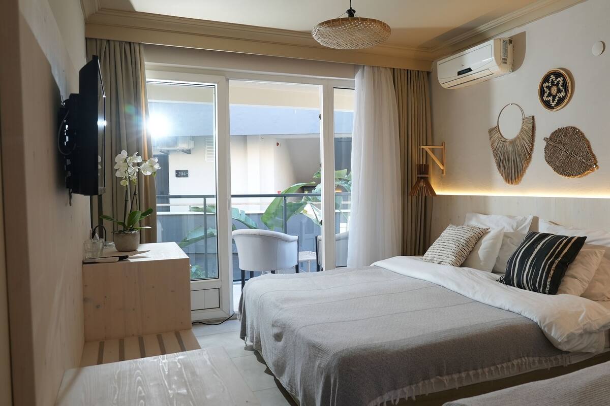 Quarto de hotel com cama, mesa de cabeceira e vista para a varanda.