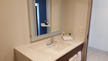 Casa de banho com lavatório branco, espelho e porta-toalhas.