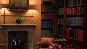 Uma biblioteca com estantes de livros, lareira e um quadro na parede.
