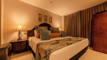 Quarto de hotel com cama, mesa de cabeceira, luminária, guarda-roupa e janela com cortinas.