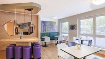 Uma sala de jantar moderna com piso de madeira, banquetas roxas e um assento fixo verde.