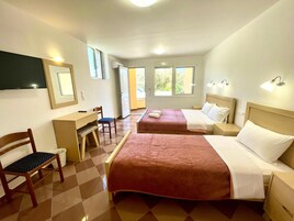Quarto de hotel com duas camas, uma escrivaninha, uma cadeira e uma televisão.
