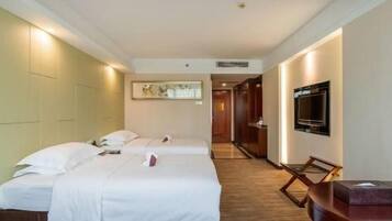 Quarto de hotel com duas camas, televisão de tela plana e piso de madeira.