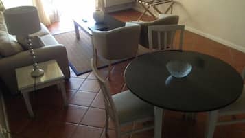 Uma sala de estar com sofá, cadeiras, uma mesinha e uma mesa redonda.