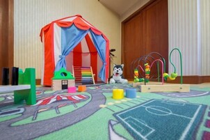 Uma área de recreação com uma tenda, brinquedos e um cachorrinho.