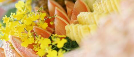 Close-up de uma tábua de frutas com laranjas fatiadas, bananas e uma flor.