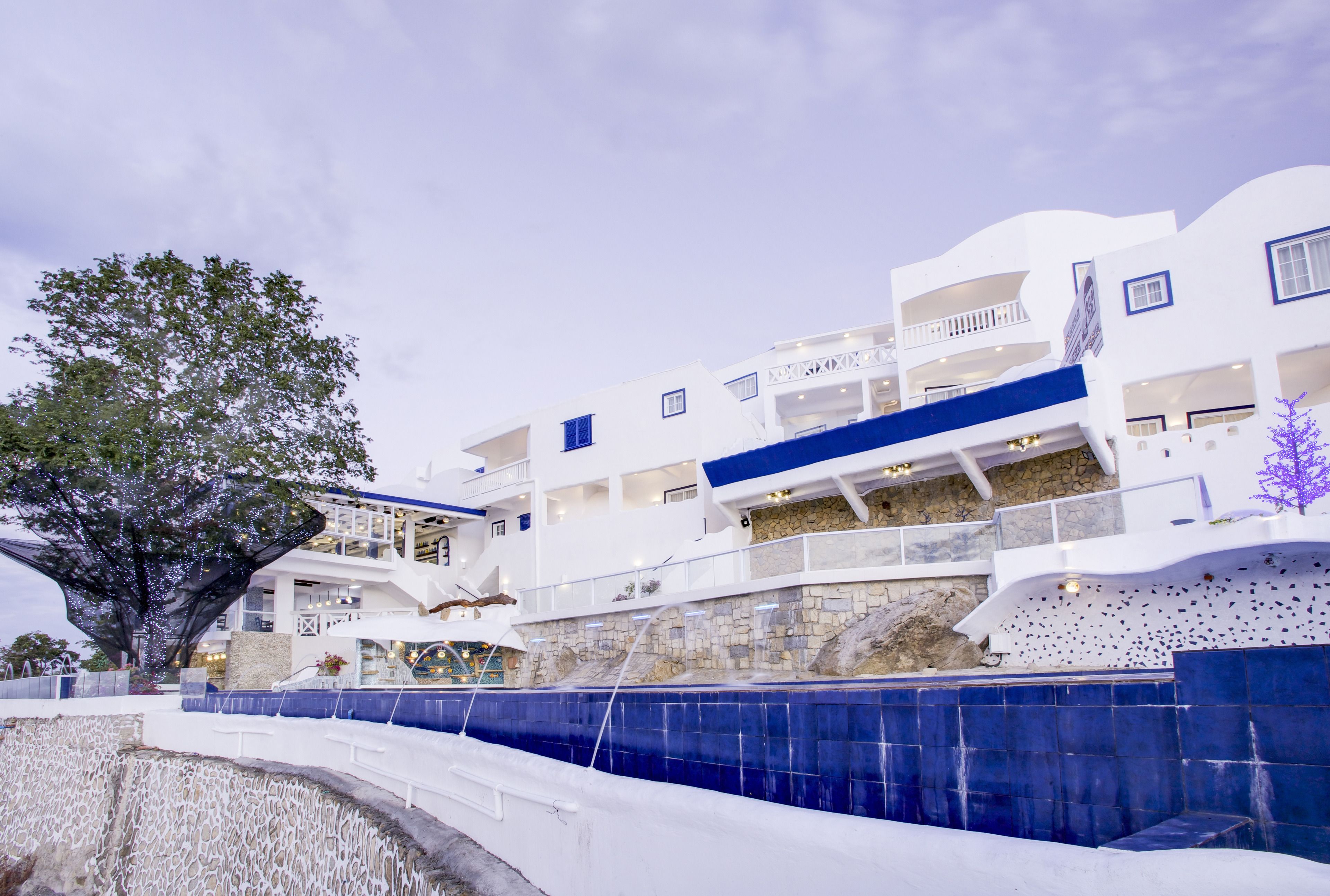 Um hotel moderno com várias varandas, área de piscina e fachada de pedra.