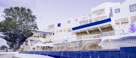 Um hotel moderno com várias varandas, área de piscina e fachada de pedra.