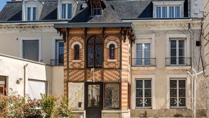 Um edifício de dois andares com fachada de tijolos, janelas em arco e uma varanda.