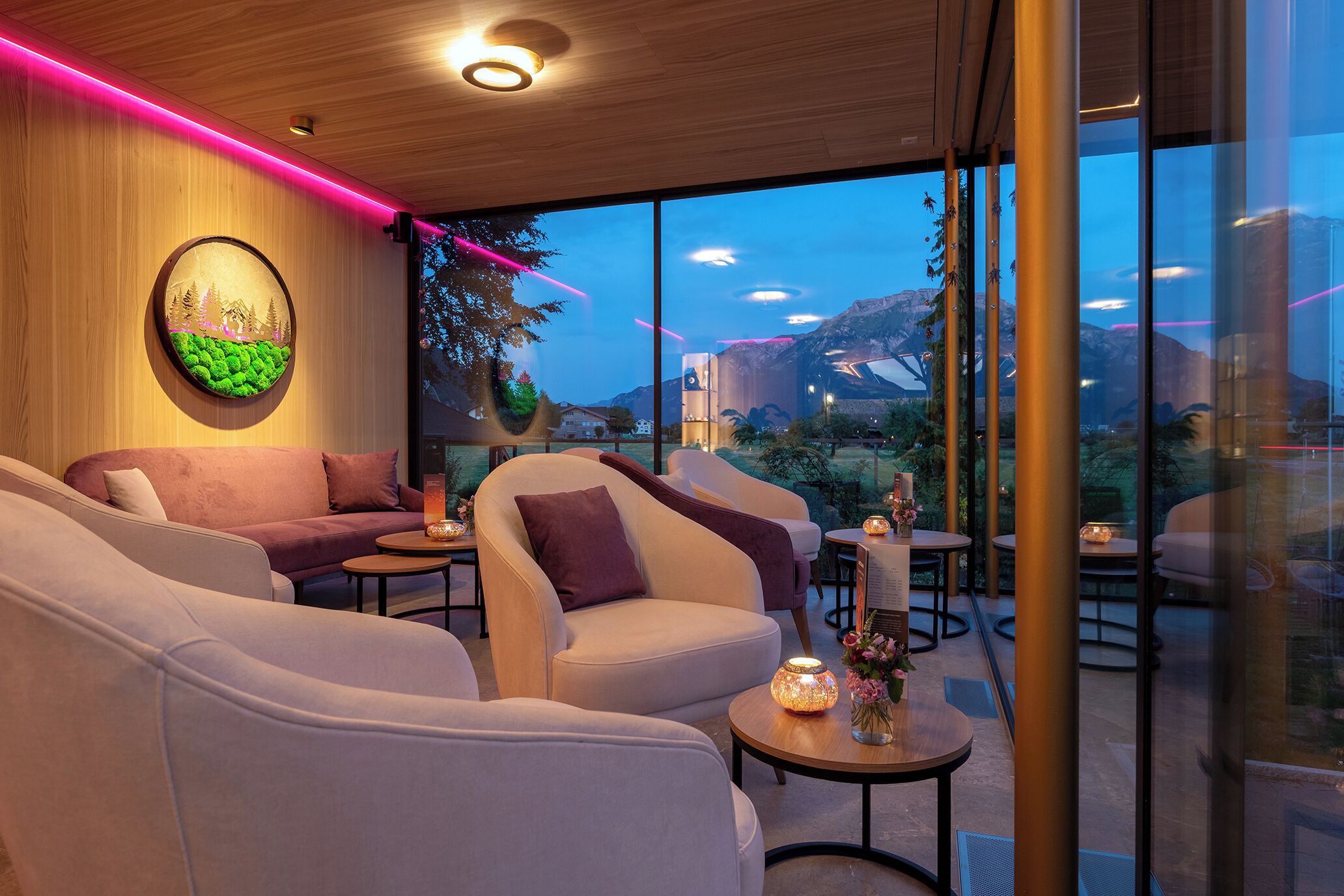 Uma área de estar moderna com sofás, uma mesa de centro e uma grande janela com vista para montanhas.