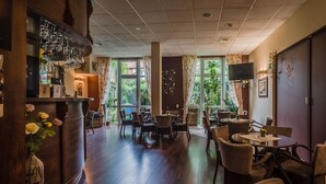 Um hall de hotel com piso de madeira, área de bar com copos pendurados e vários conjuntos de assentos.