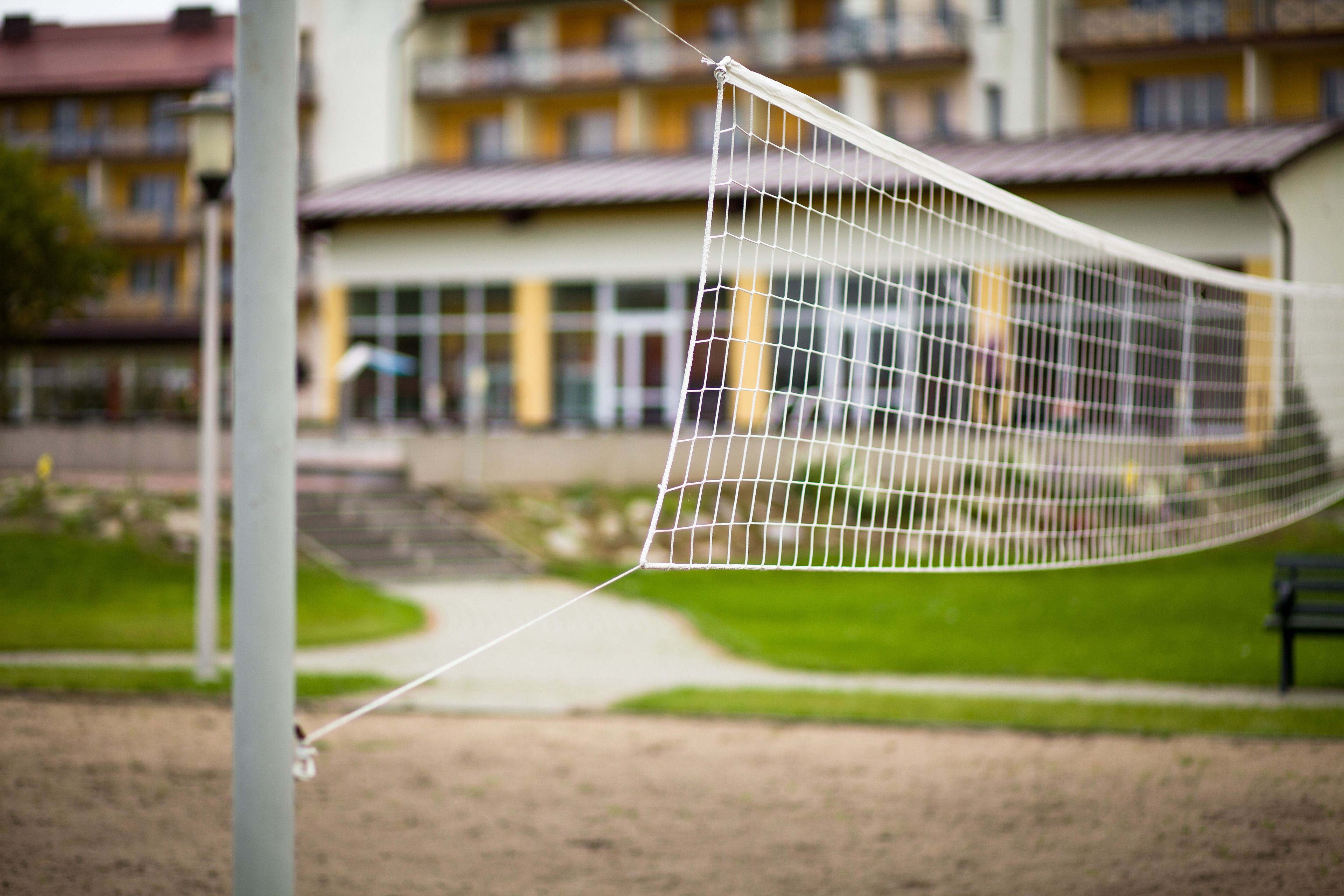 Uma quadra de voleibol com rede e um edifício ao fundo.