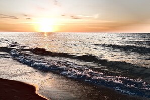 Uma praia com ondas e um pôr do sol.