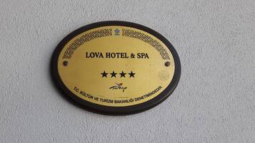 Uma placa com o texto "LOVA HOTEL & SPA" e classificação de quatro estrelas.