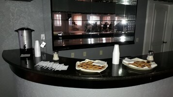 Um balcão de buffet com bandejas de comida, copos descartáveis e acompanhamentos.