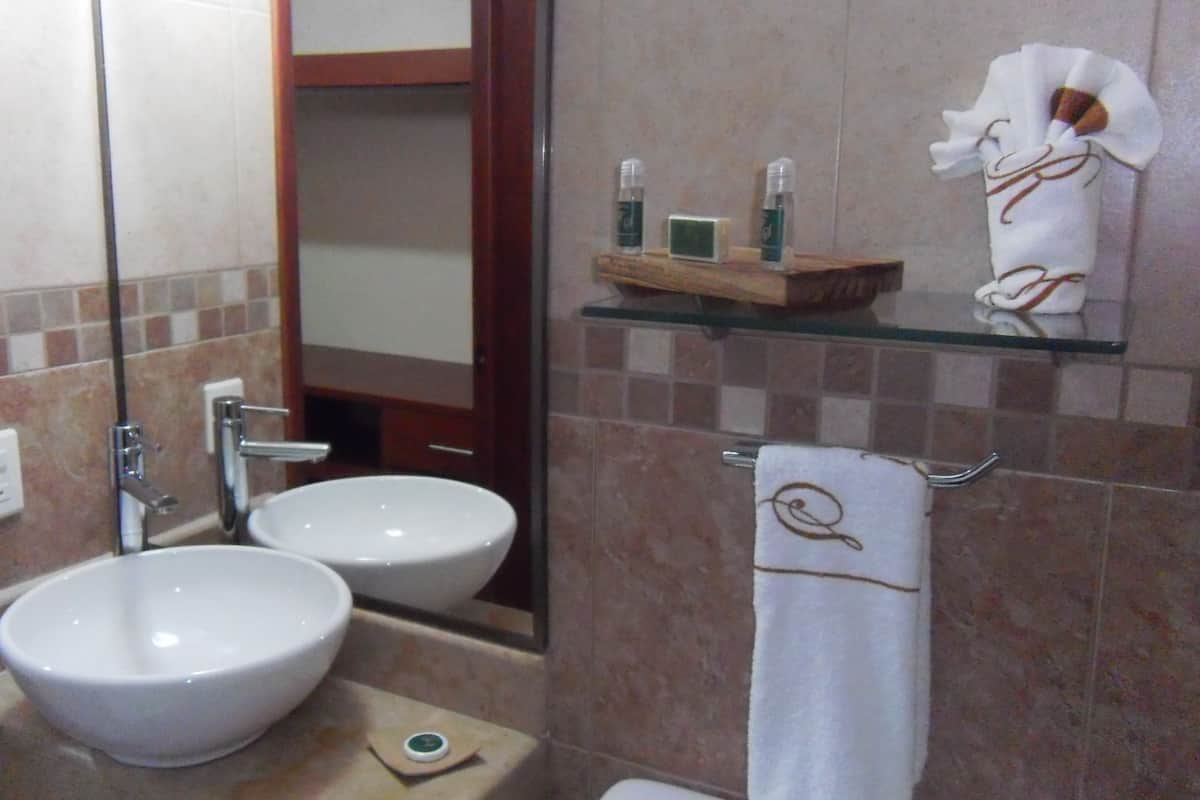 Uma casa de banho com duas pias, um espelho e um porta-toalhas.
