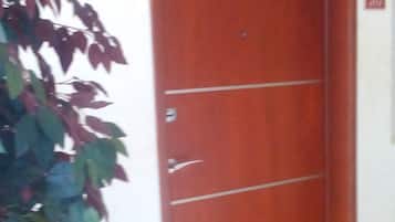 Uma porta de madeira fechada, com maçaneta e um pequeno cadeado.