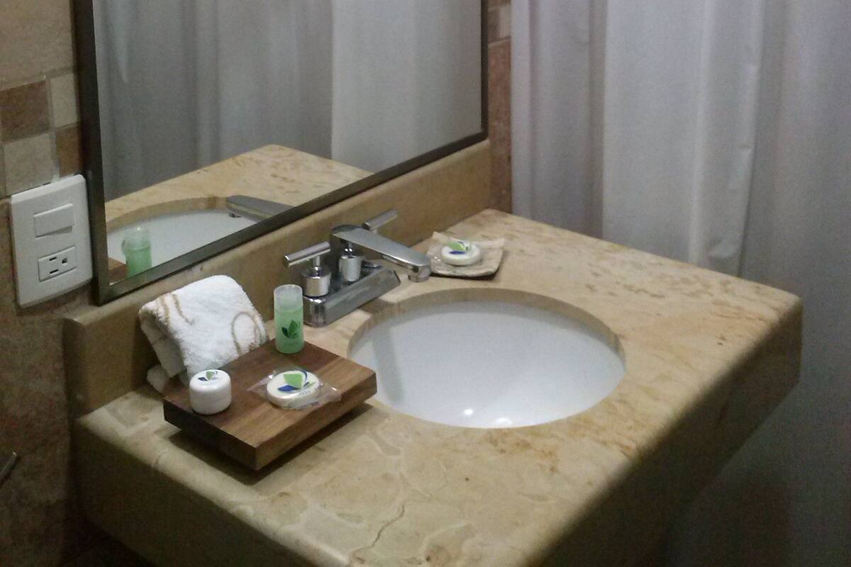 Casa de banho com um espelho grande, lavatório, toalha e cortina de chuveiro.