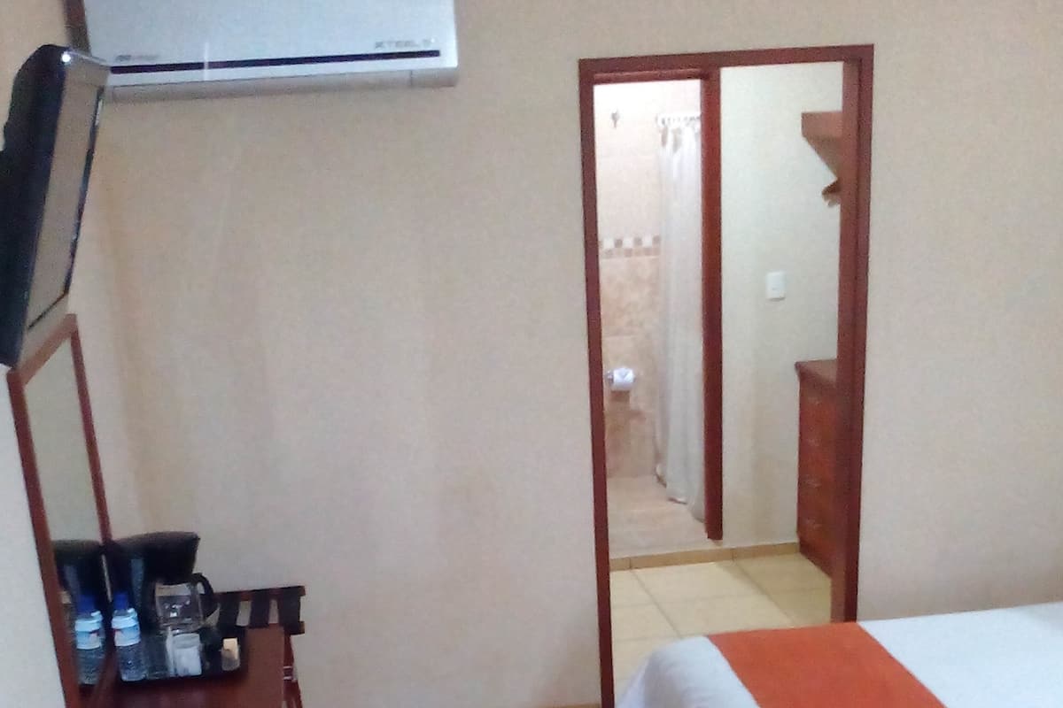 Quarto de hotel com cama, escrivaninha e guarda-roupa.