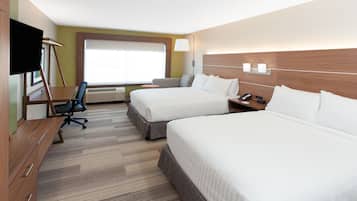 Quarto de hotel com duas camas, uma escrivaninha, uma cadeira, televisão e janela.