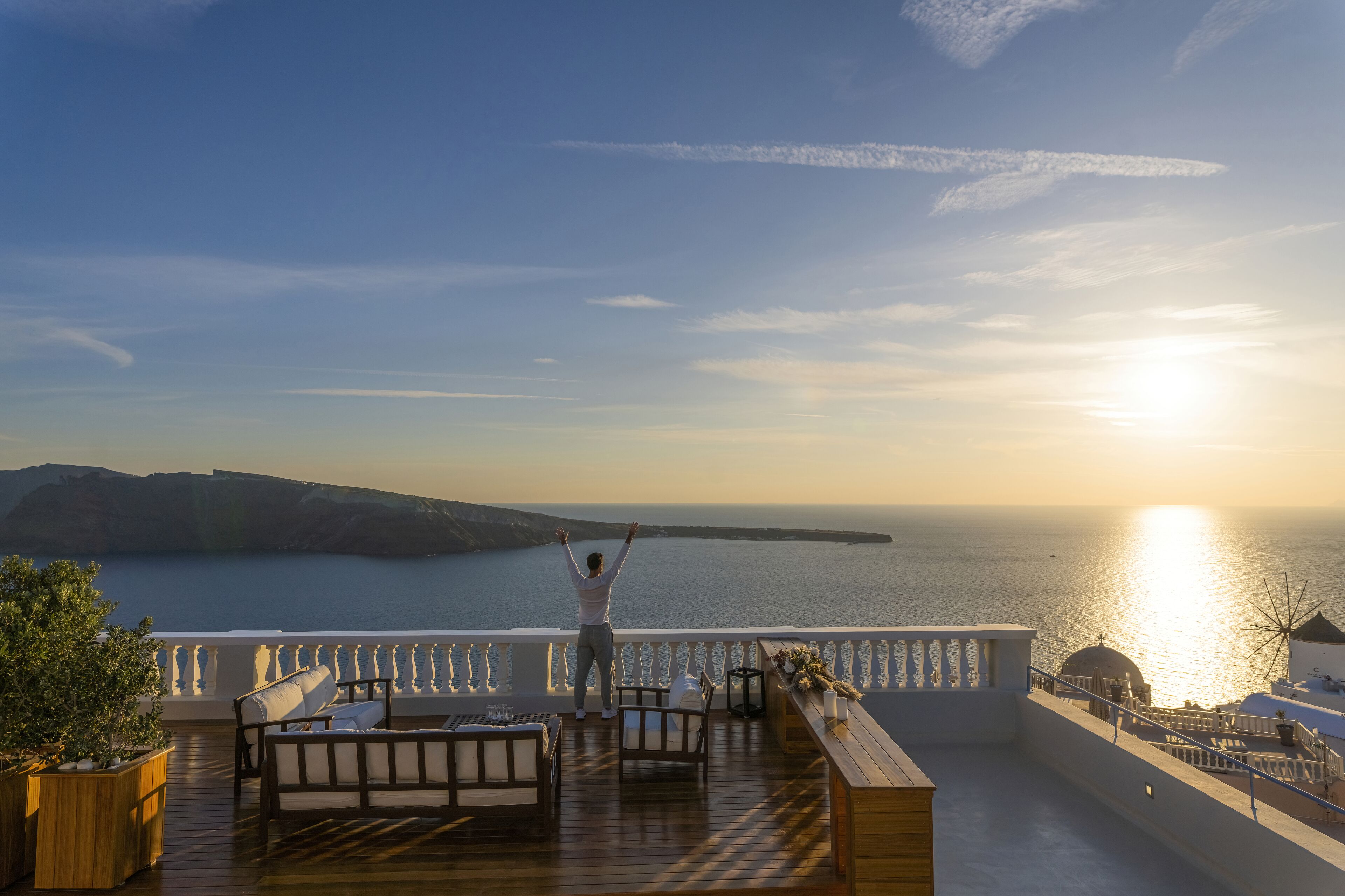 Um terraço com vista para o mar e o pôr do sol.