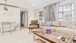 Uma sala de estar moderna com sofá, poltrona, mesa de centro e um espaço de jantar com mesa e cadeiras.